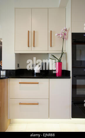 Cream fitted units in modern cream kitchen with small breakfast bar ...