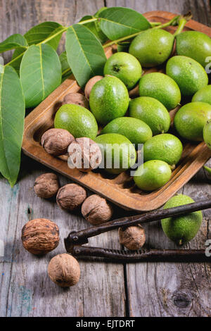 Walnuts in a wooden plate and walnut kernels. Gray background. Top view ...