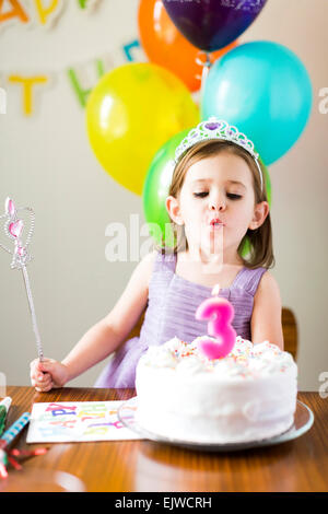 Cute birthday girl celebrating, blowing candle on cake and making wish ...