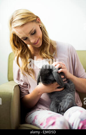 Smiling young woman with a pet rabbit. Studio picture against a white ...