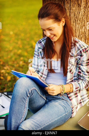 Cute hispanic girl writing in notebook in classroom at school Stock ...