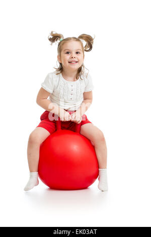 Little smiling girl jumping with big ball in gym at kindergarten or ...