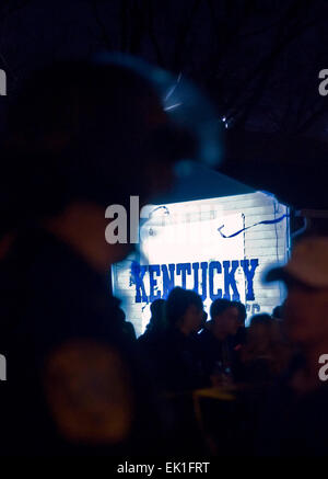 People watch a basketball game projected onto a screen in an outdoor ...