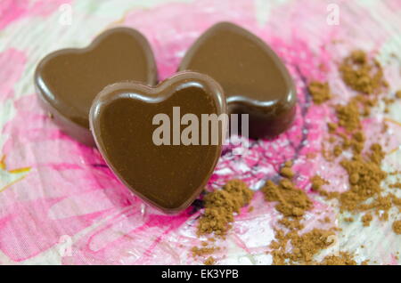 Heart-shaped plate with chocolate candies and rose flowers on turquoise ...