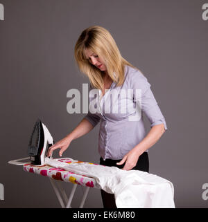 Middle age woman ironing clothes at home smiling happy doing ok sign ...