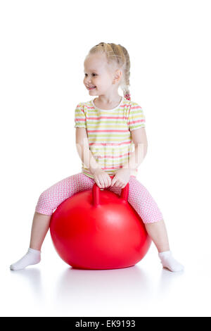 Little smiling girl jumping with big ball in gym at kindergarten or ...