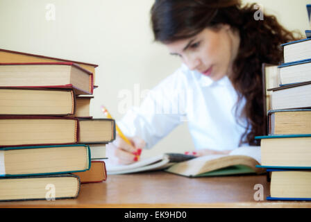 In the library - pretty female student with laptop and books working in ...
