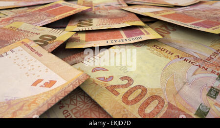 A scattered pile of south african rand bank notes bundled into value ...