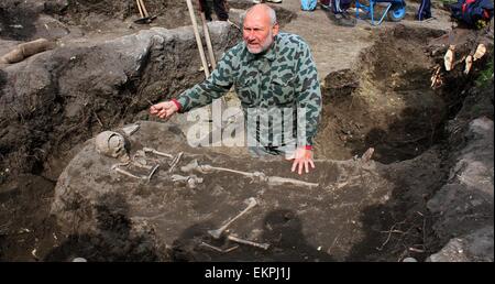 Archaelogists inspects a grave with a skeleton with an iron rod ...