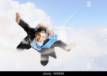 Conceptual image of young businessman flying with parachute on back ...