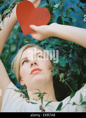 Young blonde woman holding heart calendar thinking worried about a ...