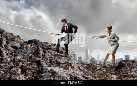 Two businessmen pulling rope atop of mountain Stock Photo - Alamy