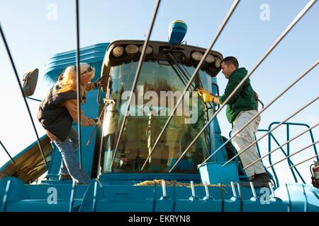 Full length farmer washing tractor wheel with hose in farm Stock Photo ...