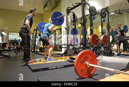 Weight training in a modern London fitness centre. A male instructor ...