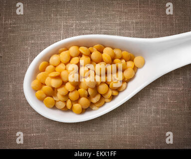 Yellow lentil in white porcelain spoon/ high resolution product photography of seed in white ...