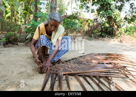 An elderly woman weaving palm leaves together to make mats, Tarawa ...