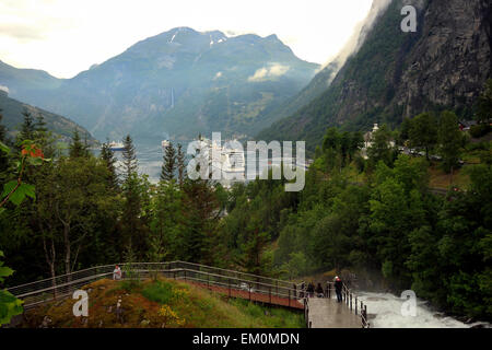 Tourists along a riverwalk, Geiranger, with a cruise ship on the ...