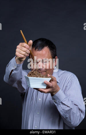 Guy getting pretty fed up with his attempts on eating with chopsticks ...