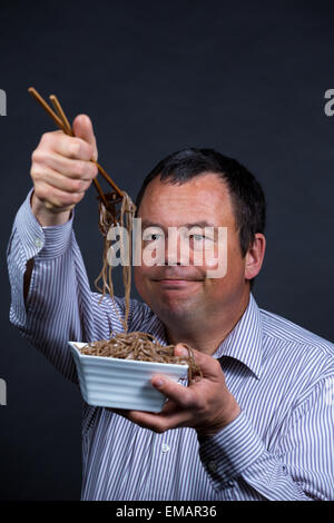 Guy getting pretty fed up with his attempts on eating with chopsticks ...