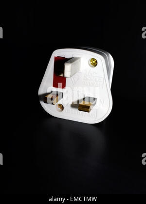 A British 3 pin electrical plug adapter photographed against a black ...