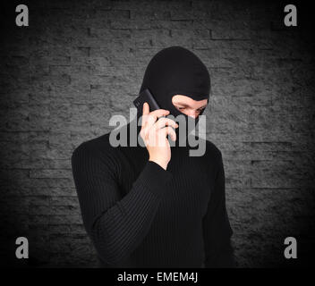robber talking on phone on a green wall background Stock Photo - Alamy