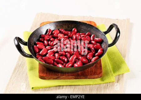 Cooked red kidney beans in a dark ceramic bowl on a rustic wooden table ...