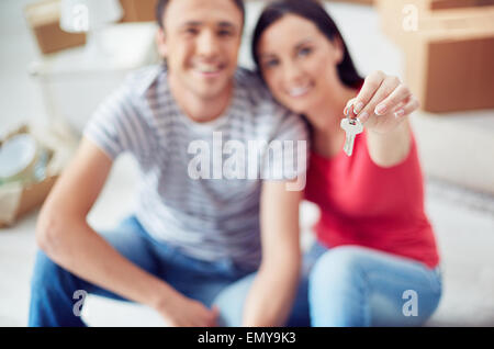 Happy young couple with key from their new house and boxes sitting on ...