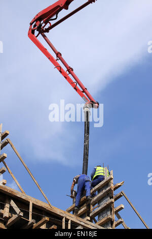 builder worker with tube from truck mounted concrete pump pouring ...