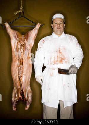 Butcher with hanging carcass and knife smiling Stock Photo - Alamy