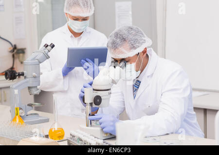 Scientists using tablet pc and microscope Stock Photo - Alamy