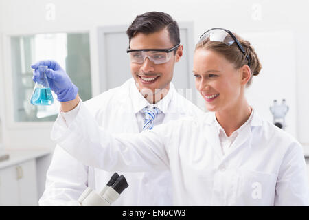 Smiling scientists looking at beaker Stock Photo - Alamy