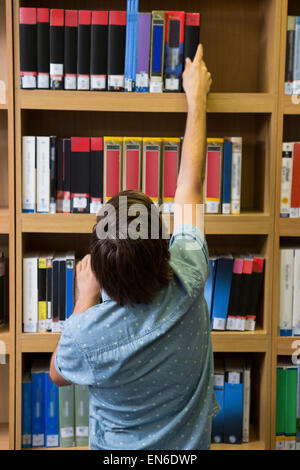Student picking a book from shelf in library Stock Photo - Alamy