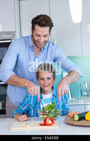 father and son preparing lunch and eating pizza together at home in the ...
