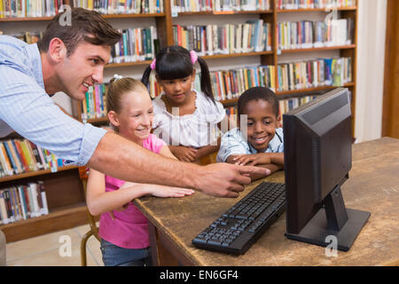 Teacher and pupils using computer at library Stock Photo - Alamy