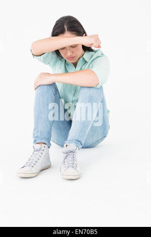 Sad woman sitting on floor and looking to camera. She is lonely and ...