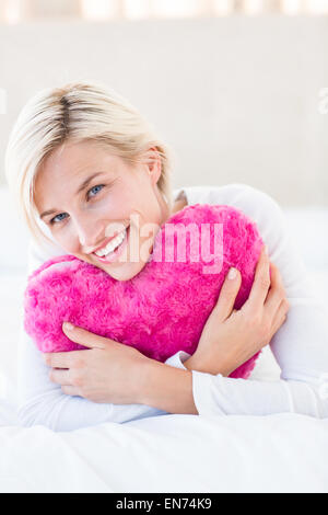 Young blonde woman holding heart calendar angry and mad raising fist ...