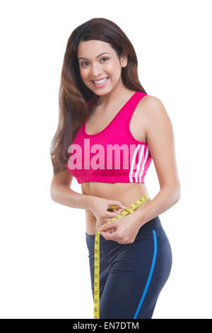 Young Indian woman measuring her waist at home while checking fitness ...