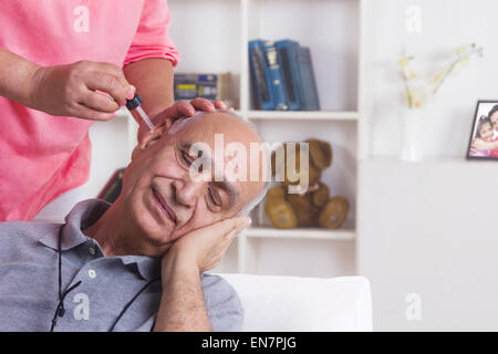 Old man getting ear drops put in Stock Photo - Alamy
