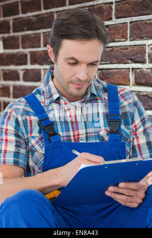 Plumber writing on a clipboard Stock Photo - Alamy