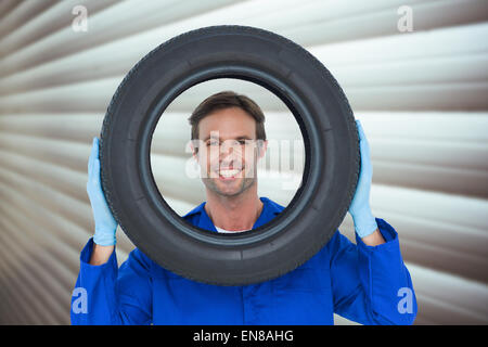Confident mechanic looking through tire Stock Photo - Alamy