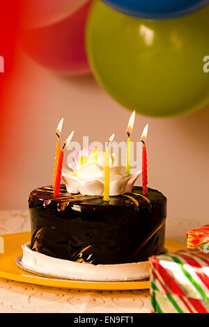 Burning candle, balloon and gift boxes on light wooden background ...
