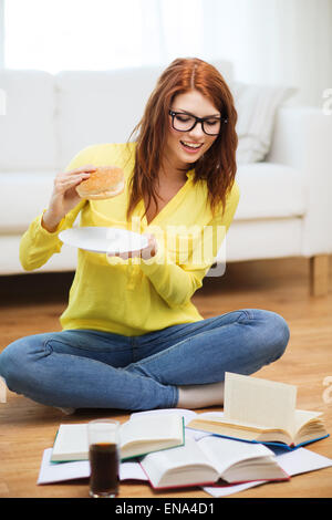 Girl doing homework and eating junk food Stock Photo - Alamy