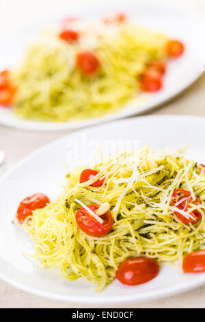 Homemade angel hair pasta with pesto sauce, roasted cherry tomatoes and ...