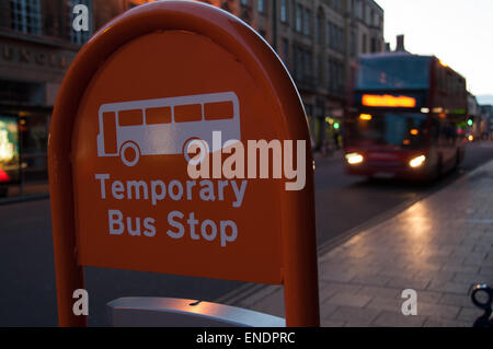 Temporary bus stop sign in a rural village tree lined road with no ...