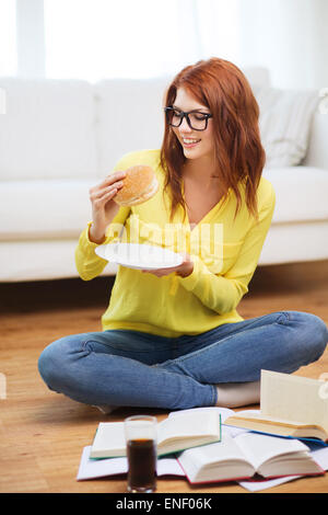 Girl doing homework and eating junk food Stock Photo - Alamy
