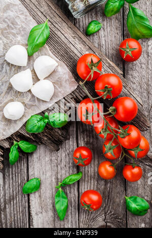 Cheese, cherry tomatoes and basil on a dark background Stock Photo - Alamy