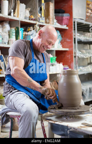 Man forming clay on a potters wheel at a ceramics factory in Deruta ...