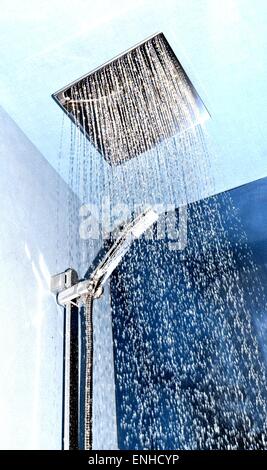 A detail of a bathroom's shower with marble tiled walls, chrome ...