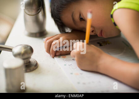 A Japanese boy studies Japanese homework in a kitchen as his mom looks ...