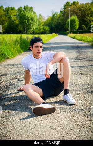 Handsome young sportsman resting after hard workout, holding water ...